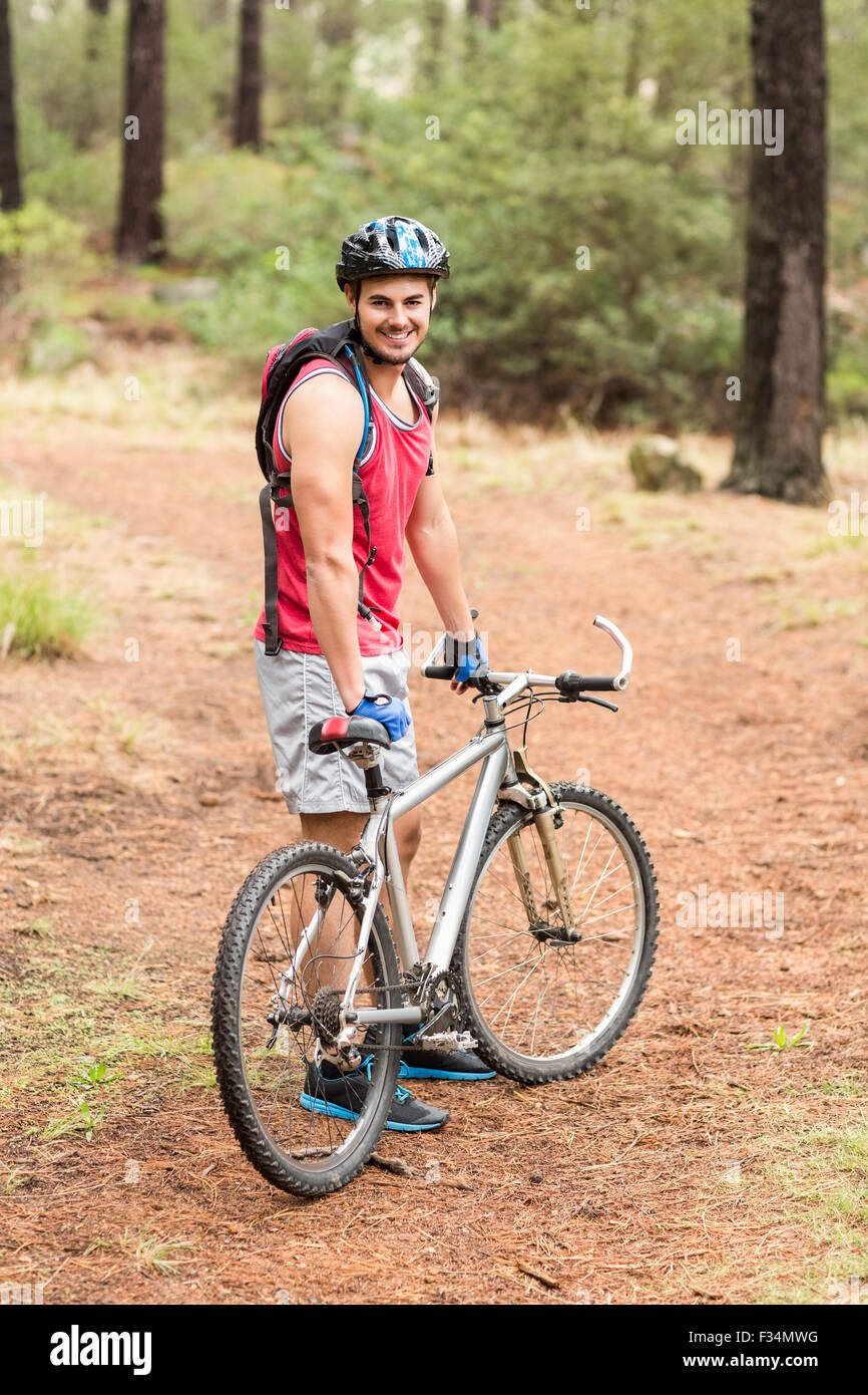 Happy handsome biker holding bike and looking at camera Stock Photo - Alamy
