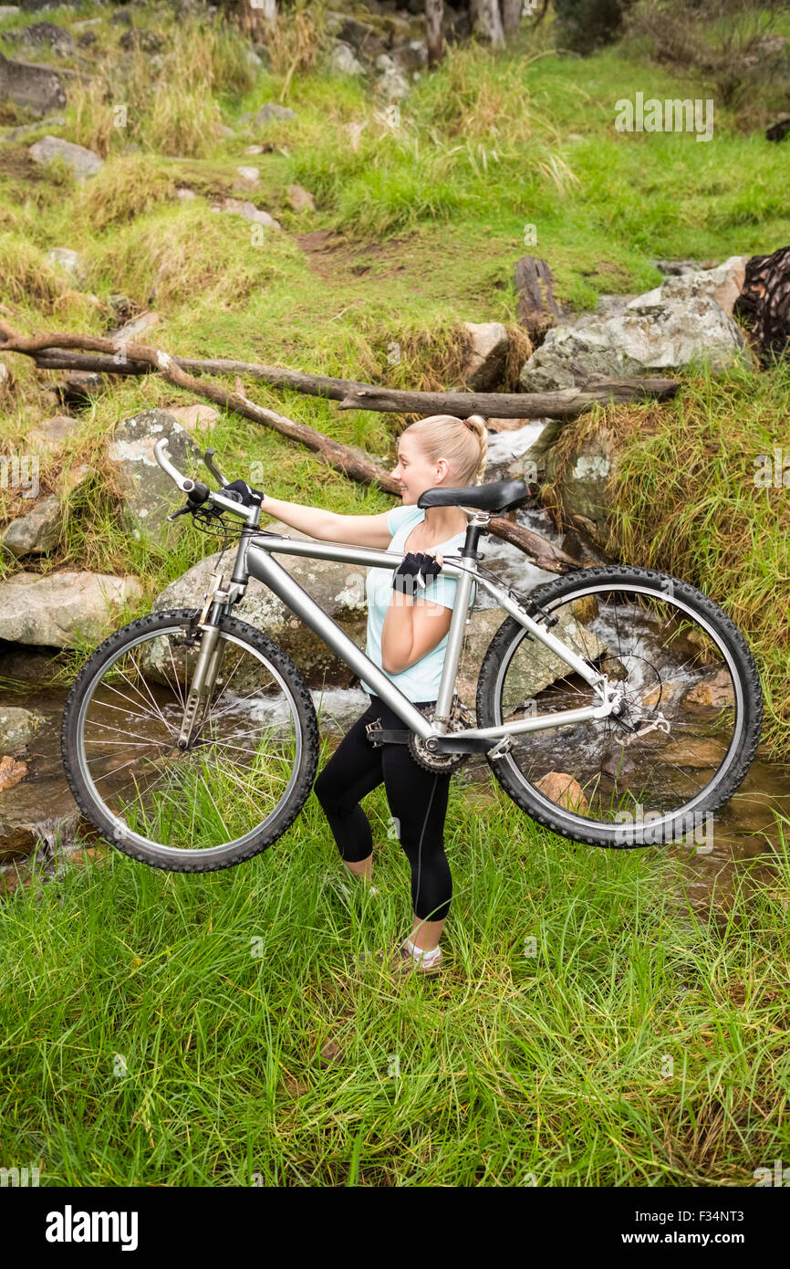 Side view of a fit woman lifting her bike Stock Photo - Alamy
