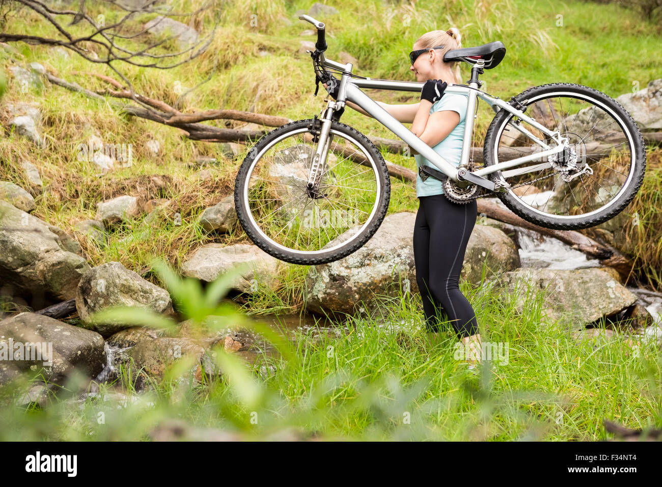 Side view of a fit woman lifting her bike Stock Photo - Alamy