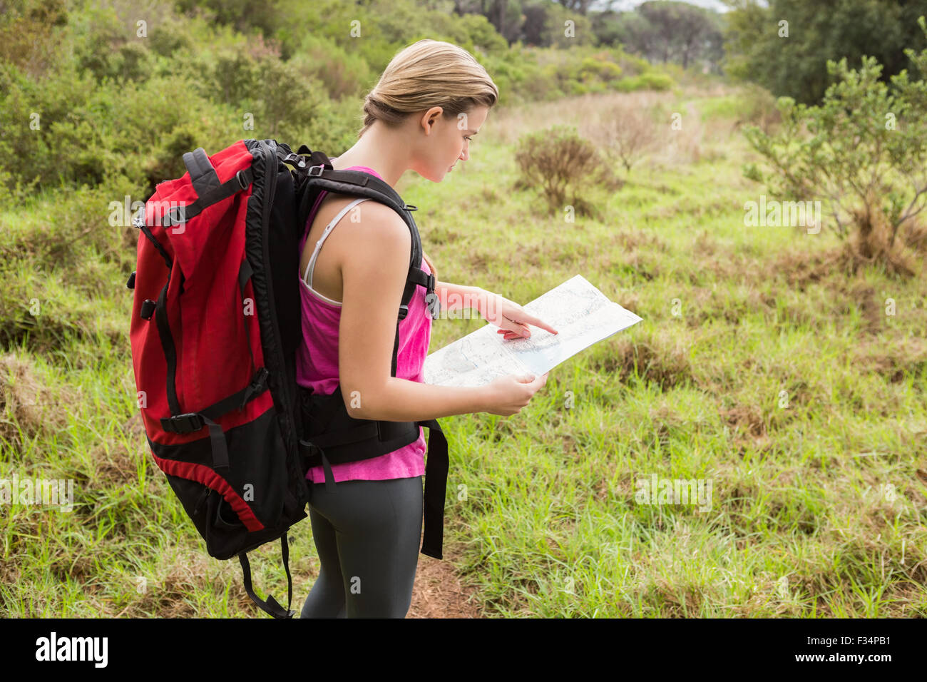 Blonde hiker with backpack reading map Stock Photo - Alamy