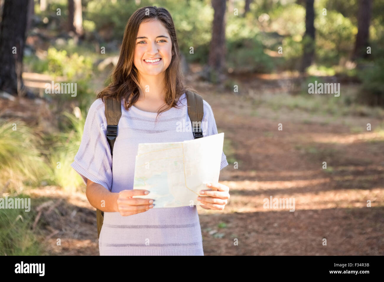 Pretty brunette hiker with map smiling Stock Photo - Alamy