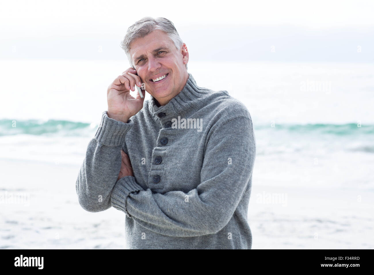 Smiling man standing and on his phone Stock Photo - Alamy