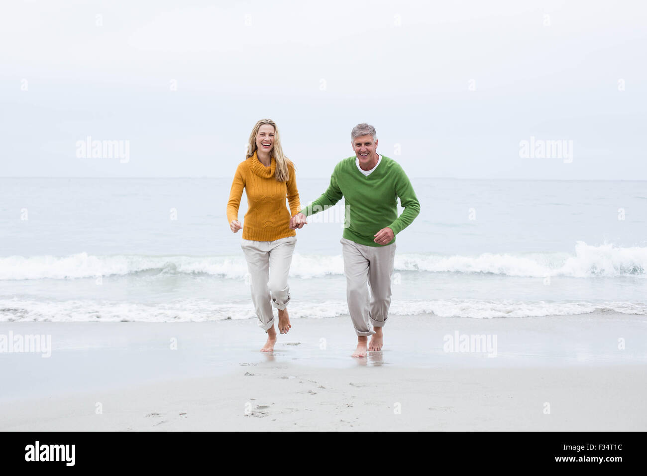 Happy couple holding hands and running Stock Photo - Alamy