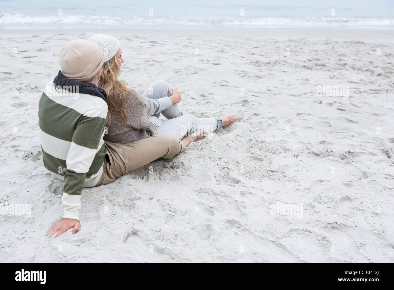 Cute couple sitting in the sand Stock Photo - Alamy