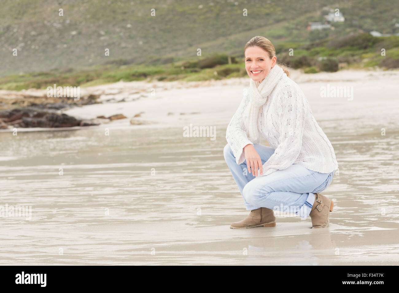 Woman crouching at the shore Stock Photo - Alamy