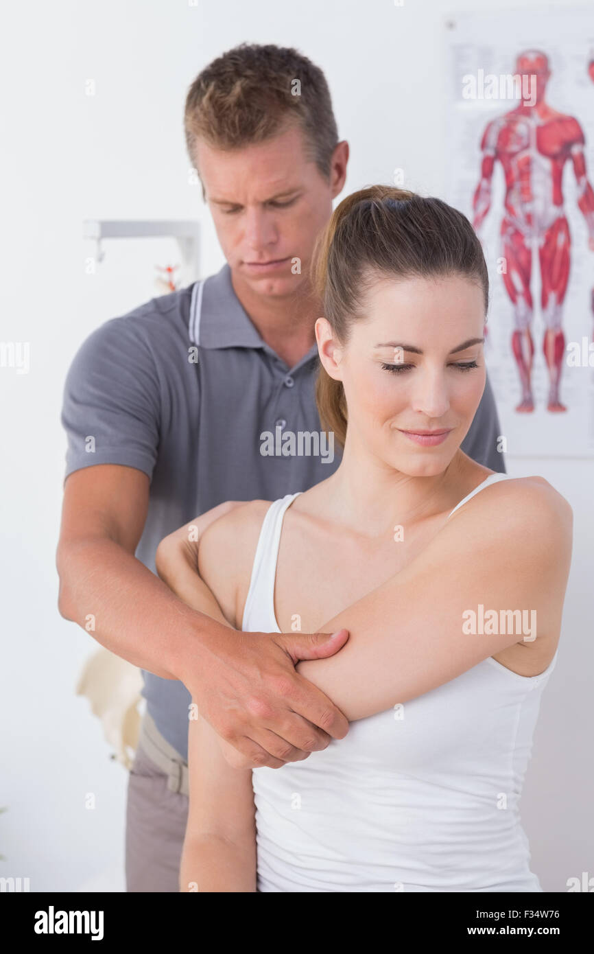 Doctor stretching a young woman arm Stock Photo - Alamy