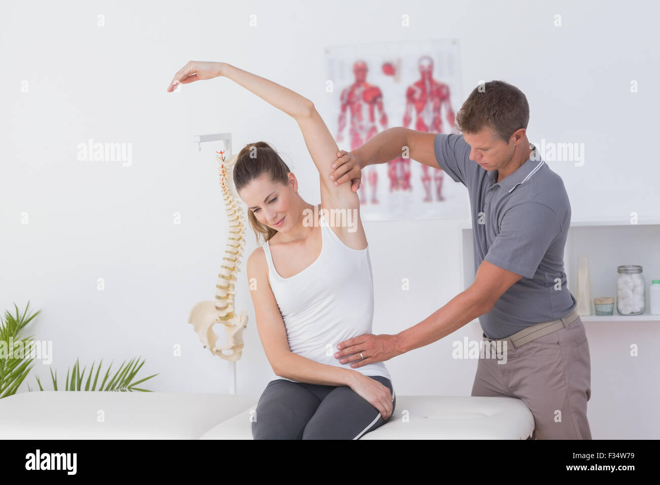 Doctor stretching a young woman arm Stock Photo - Alamy