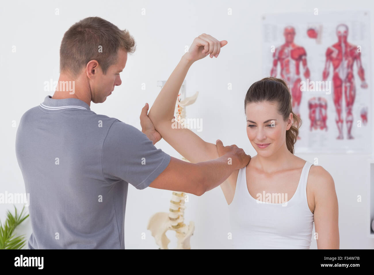 Doctor stretching a young woman arm Stock Photo - Alamy