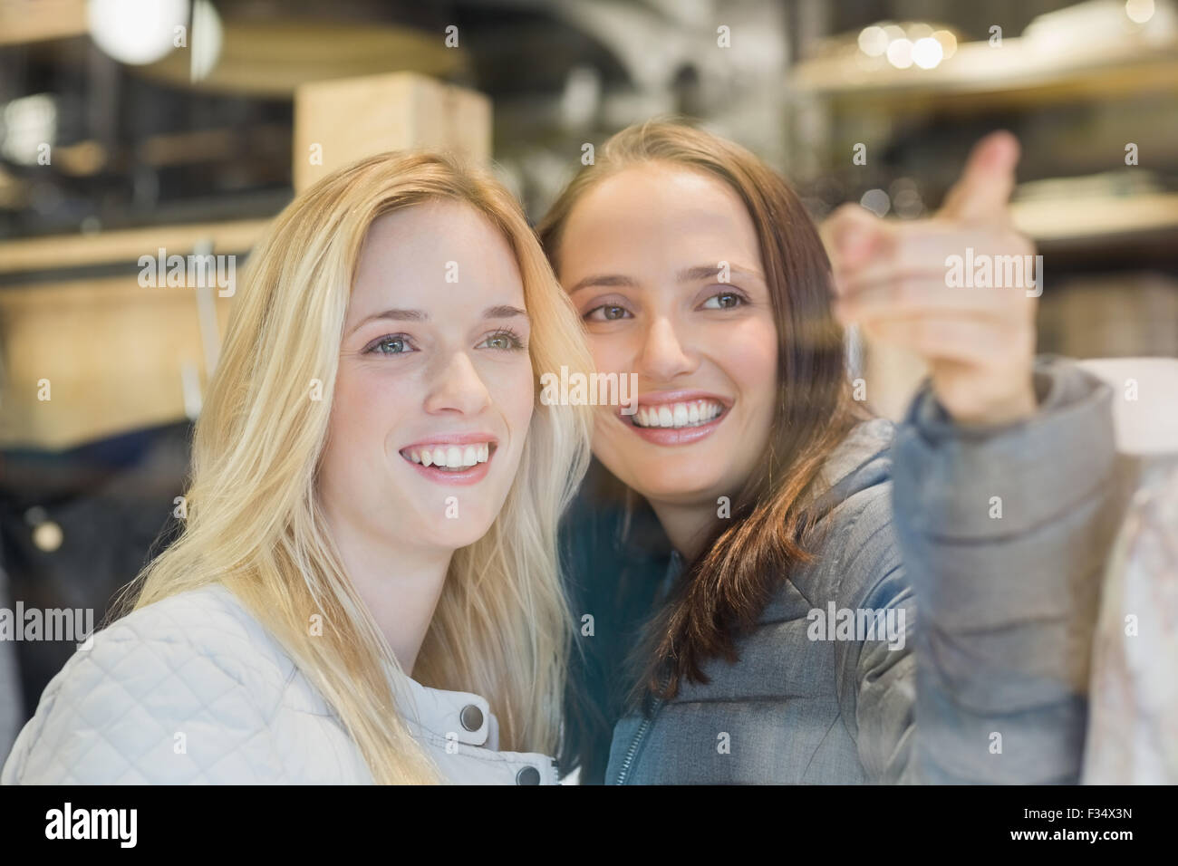 Two smiling female friends pointing away Stock Photo - Alamy