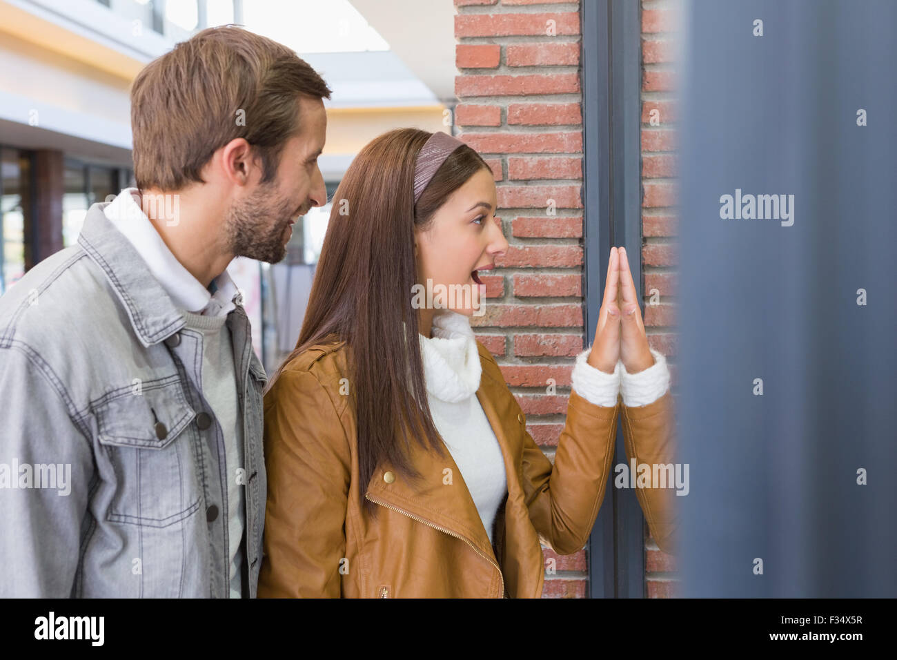 Young happy smiling couple looking at a window Stock Photo - Alamy