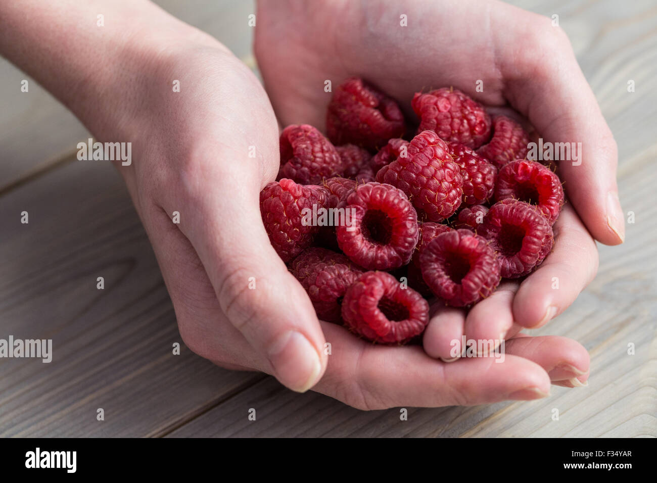 Woman showing handful of raspberries Stock Photo - Alamy