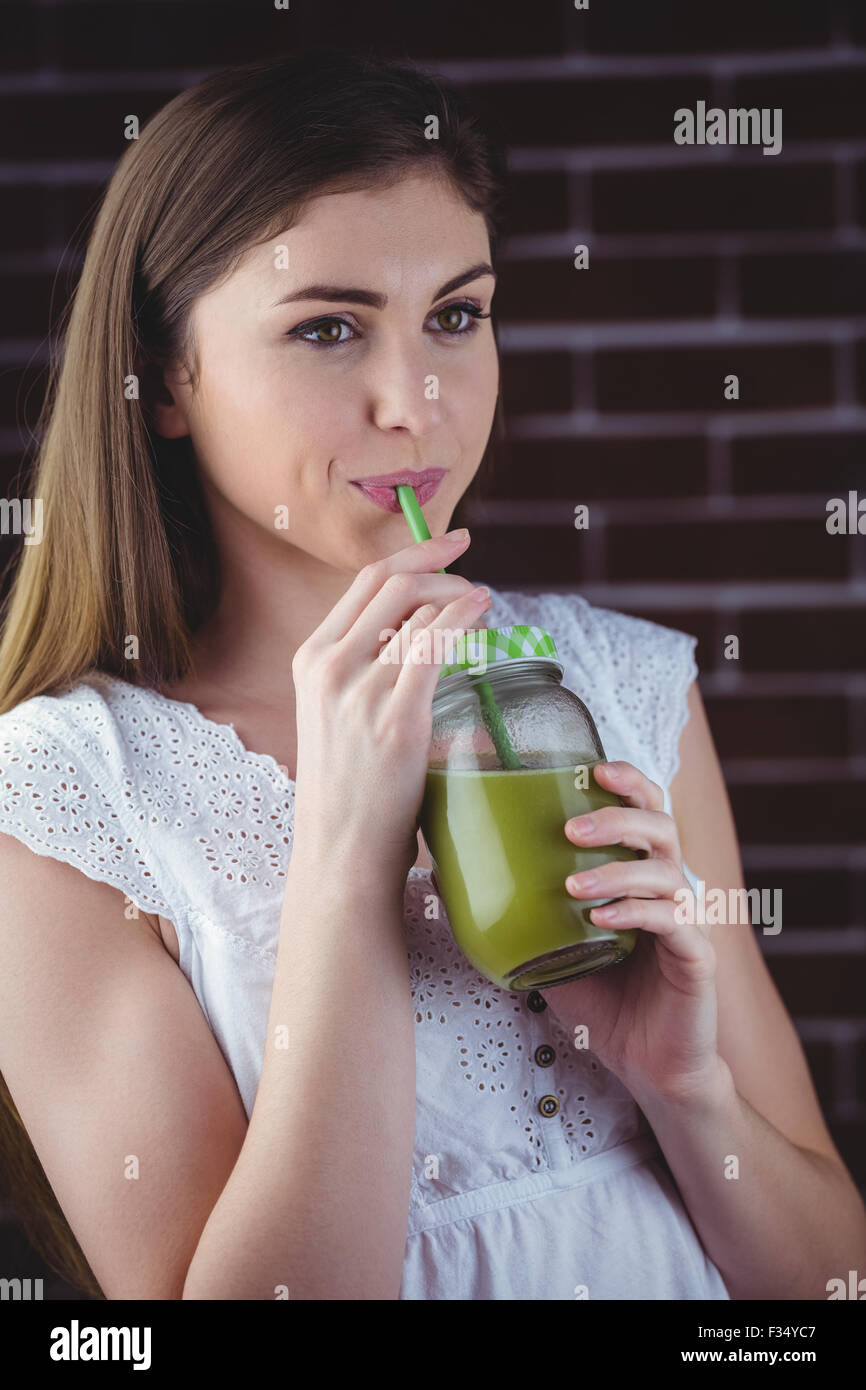 Pretty woman sipping on green juice Stock Photo - Alamy