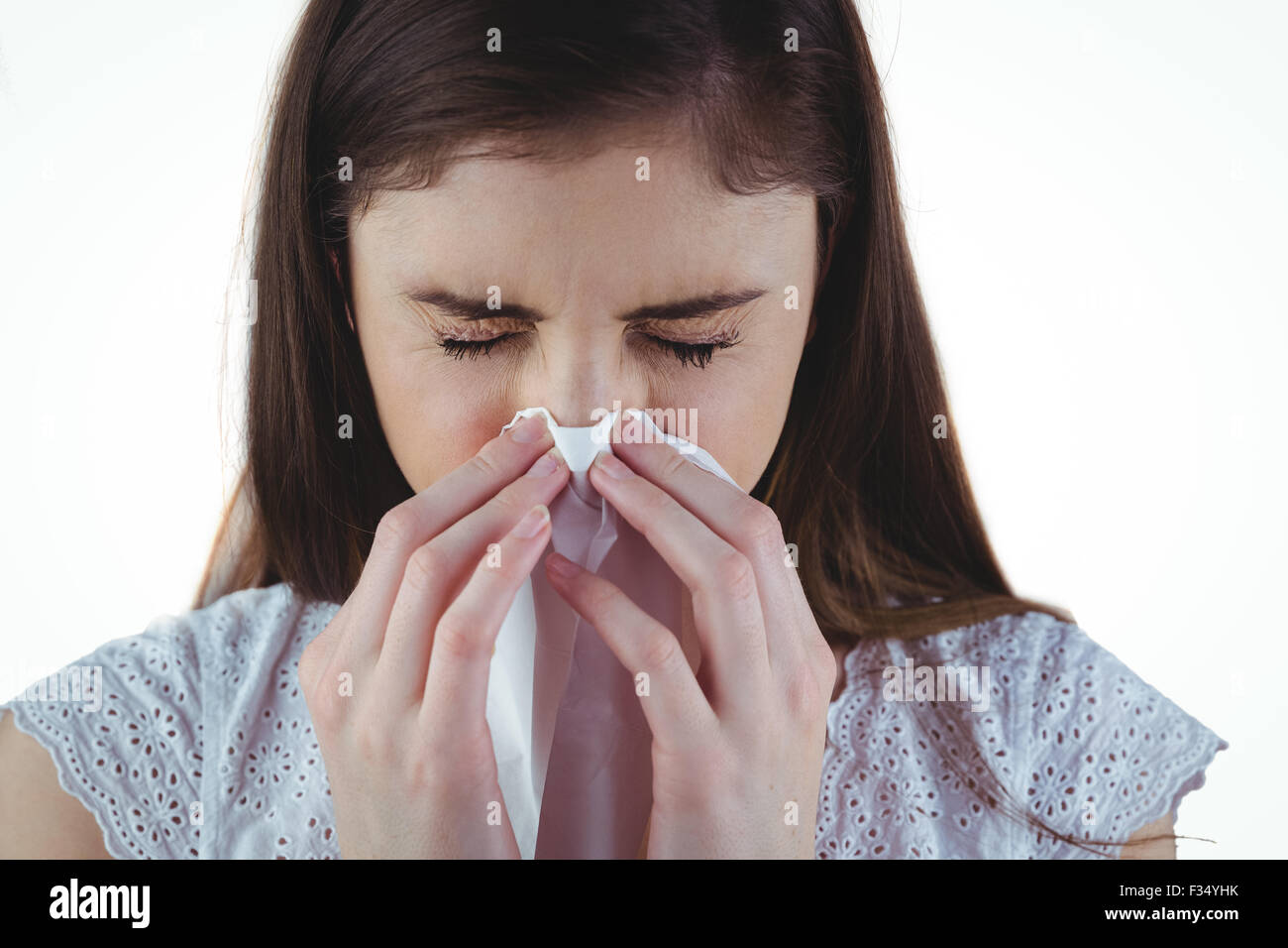 Sick brunette blowing her nose Stock Photo - Alamy