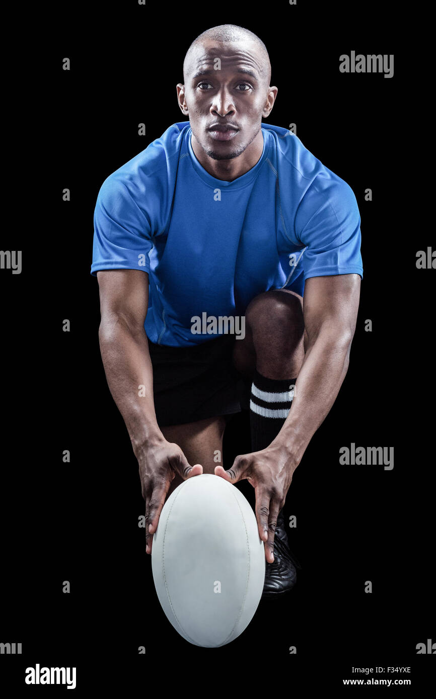 Portrait of rugby player holding ball while kneeling Stock Photo - Alamy