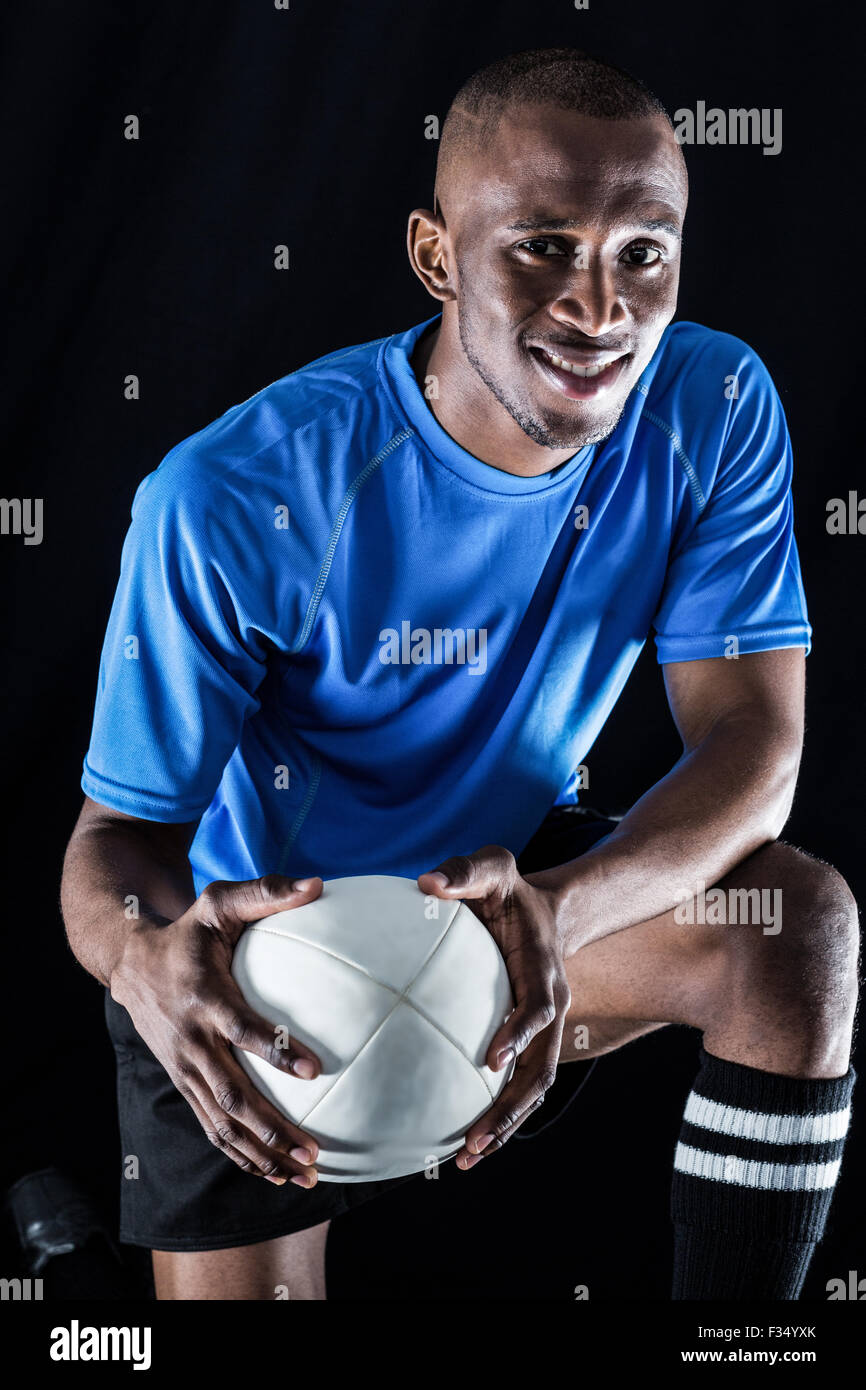 Portrait of rugby player with ball smiling while kneeling Stock Photo ...
