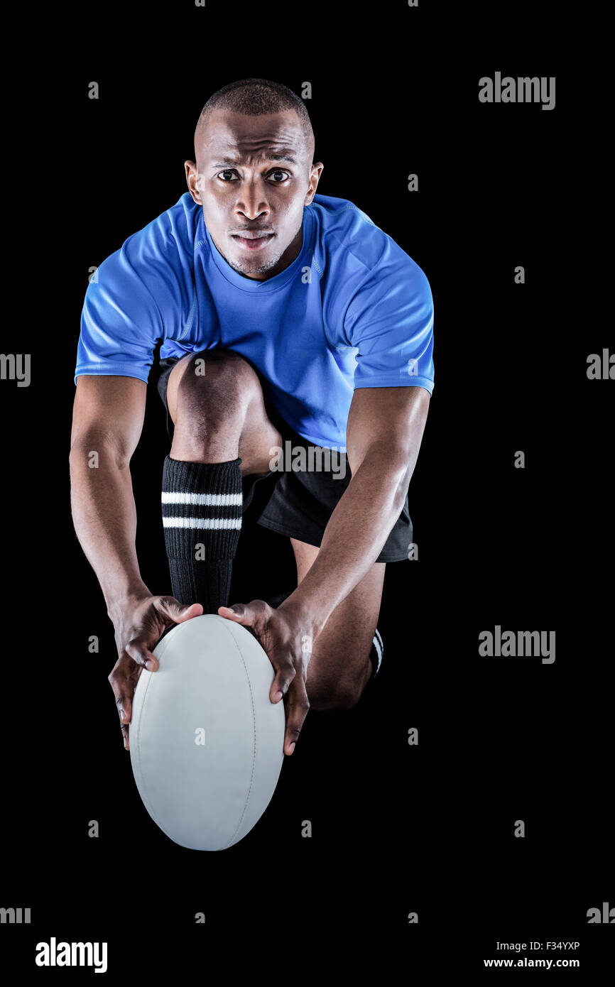 Portrait of rugby player kneeling and holding ball Stock Photo - Alamy
