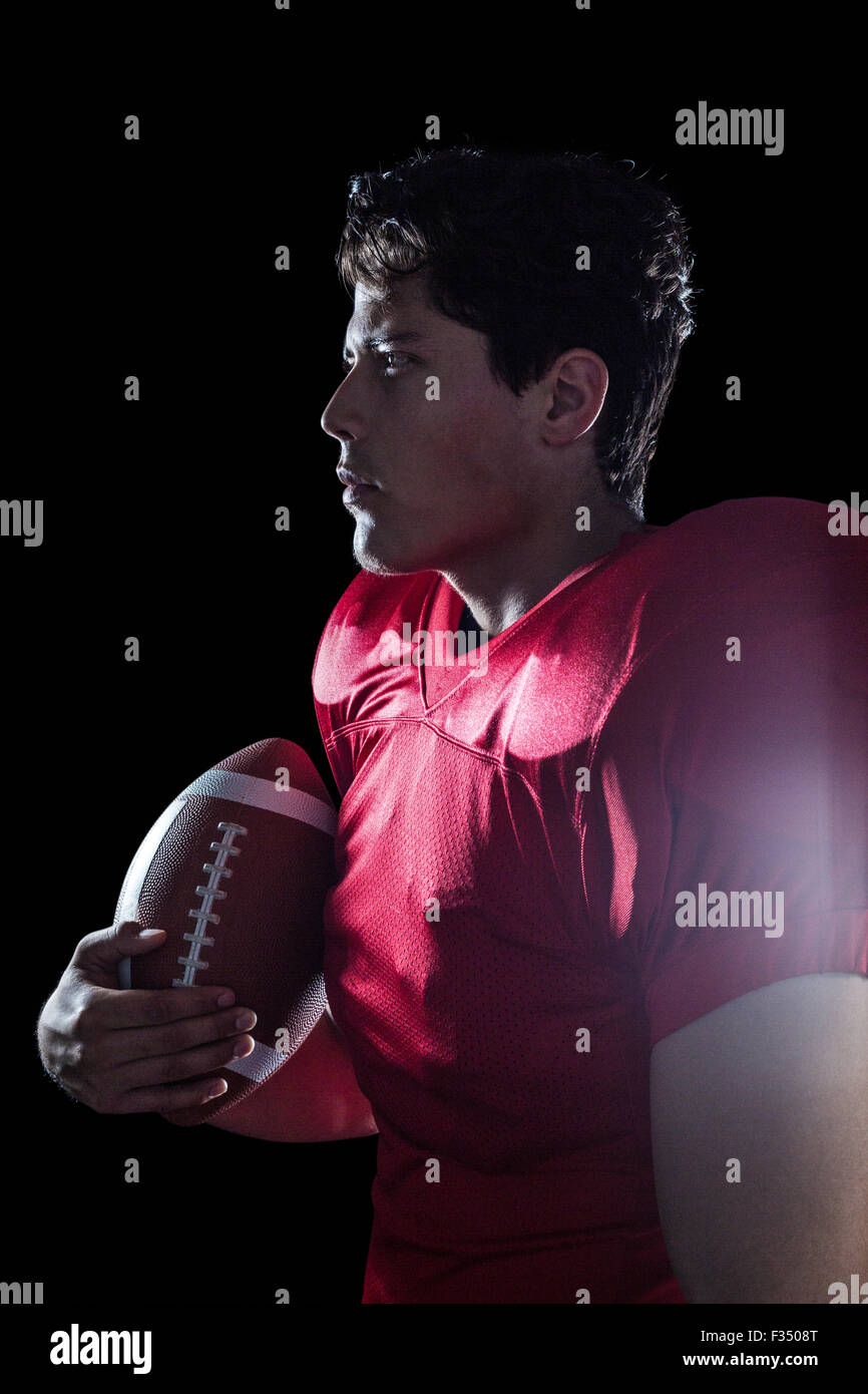 Side view of confident American football player holding ball Stock ...