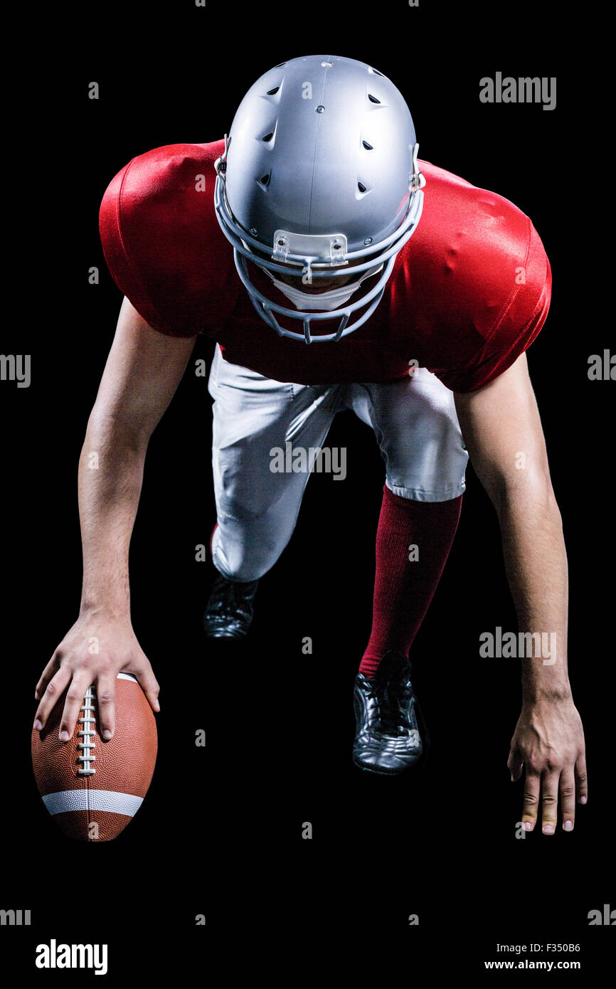 American football player taking position while holding ball Stock Photo ...