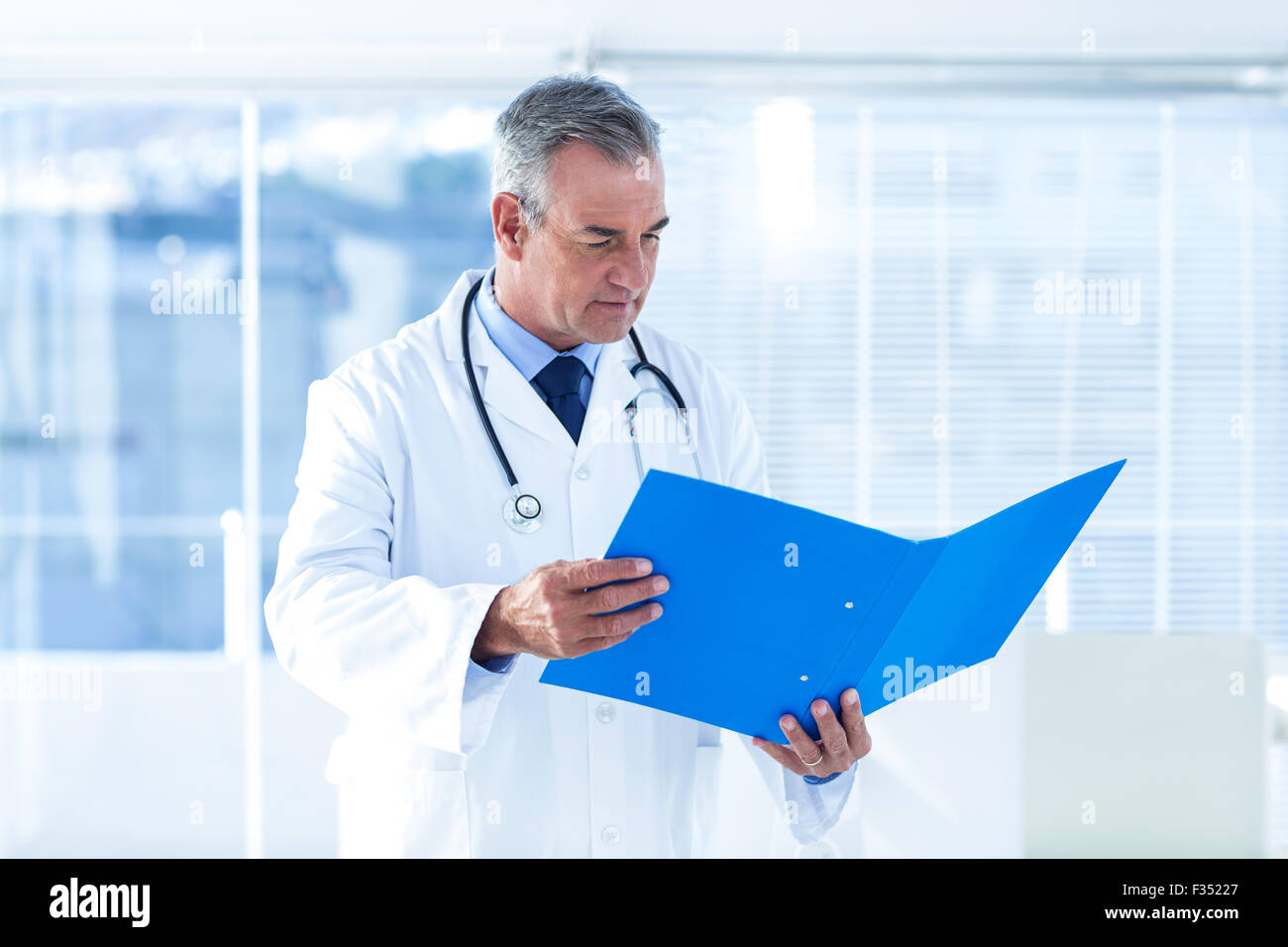 Male doctor reading document in hospital Stock Photo - Alamy
