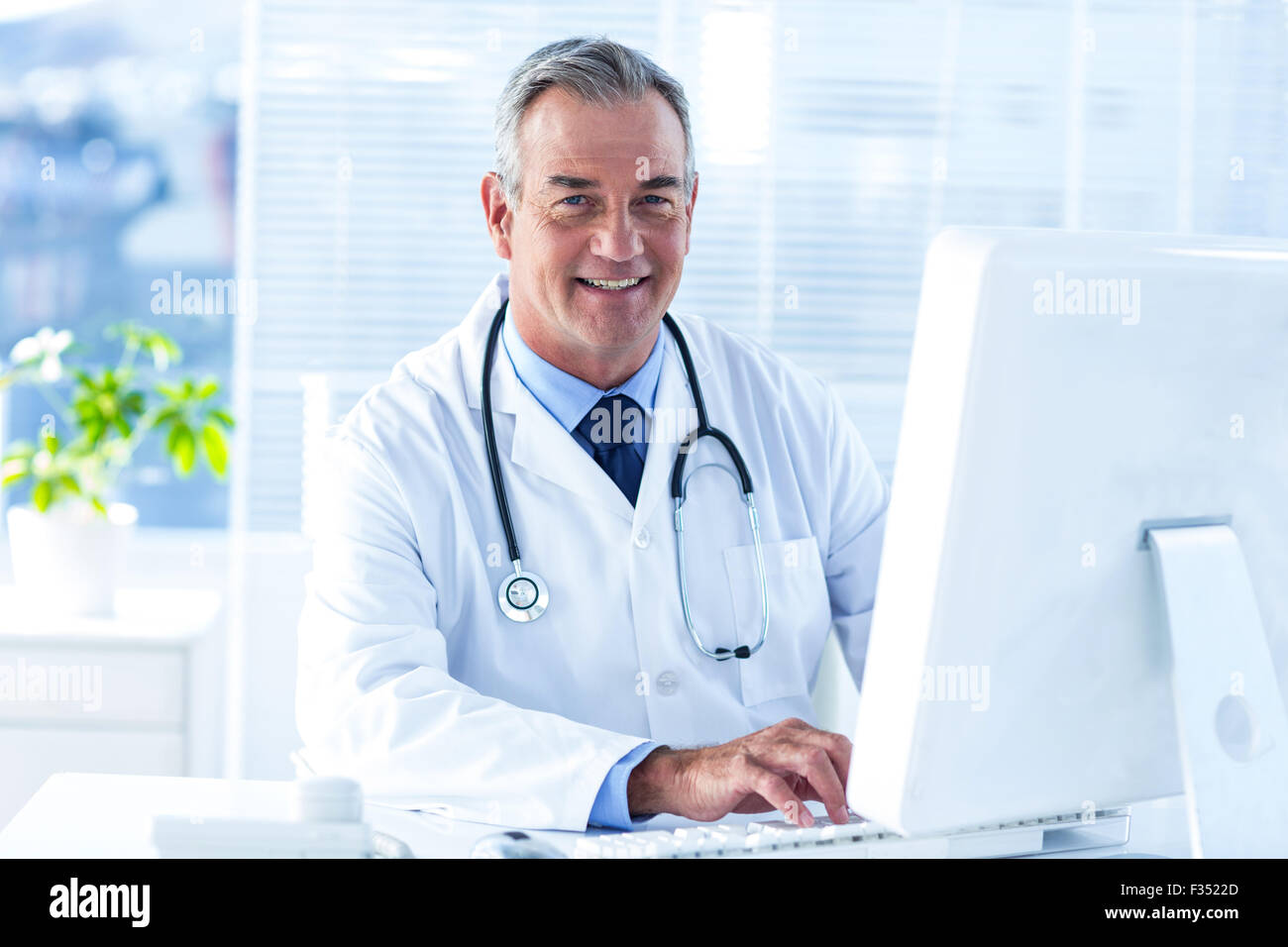 Smiling male doctor using computer in clinic Stock Photo - Alamy