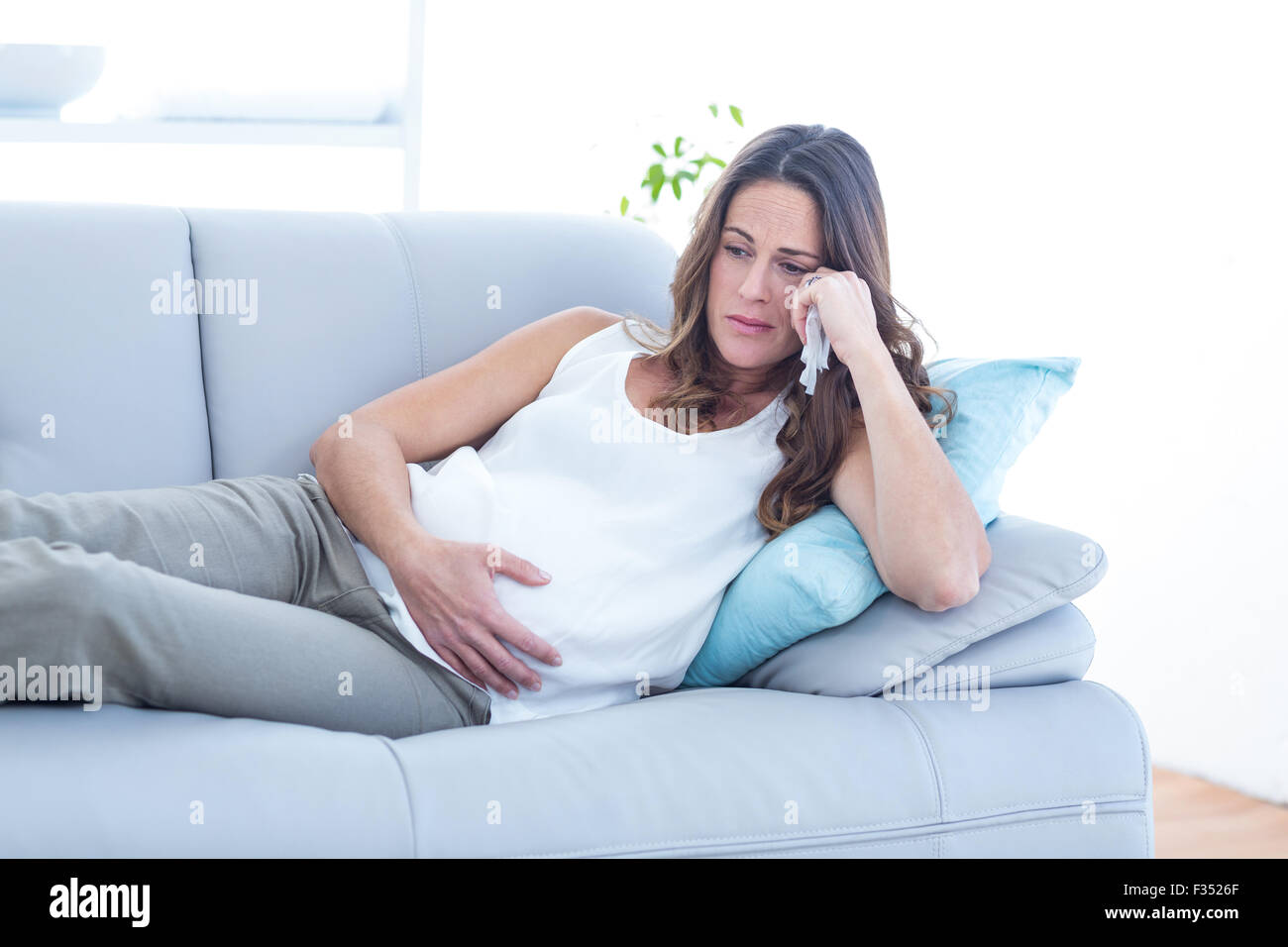 Sad pregnant woman lying on sofa Stock Photo - Alamy