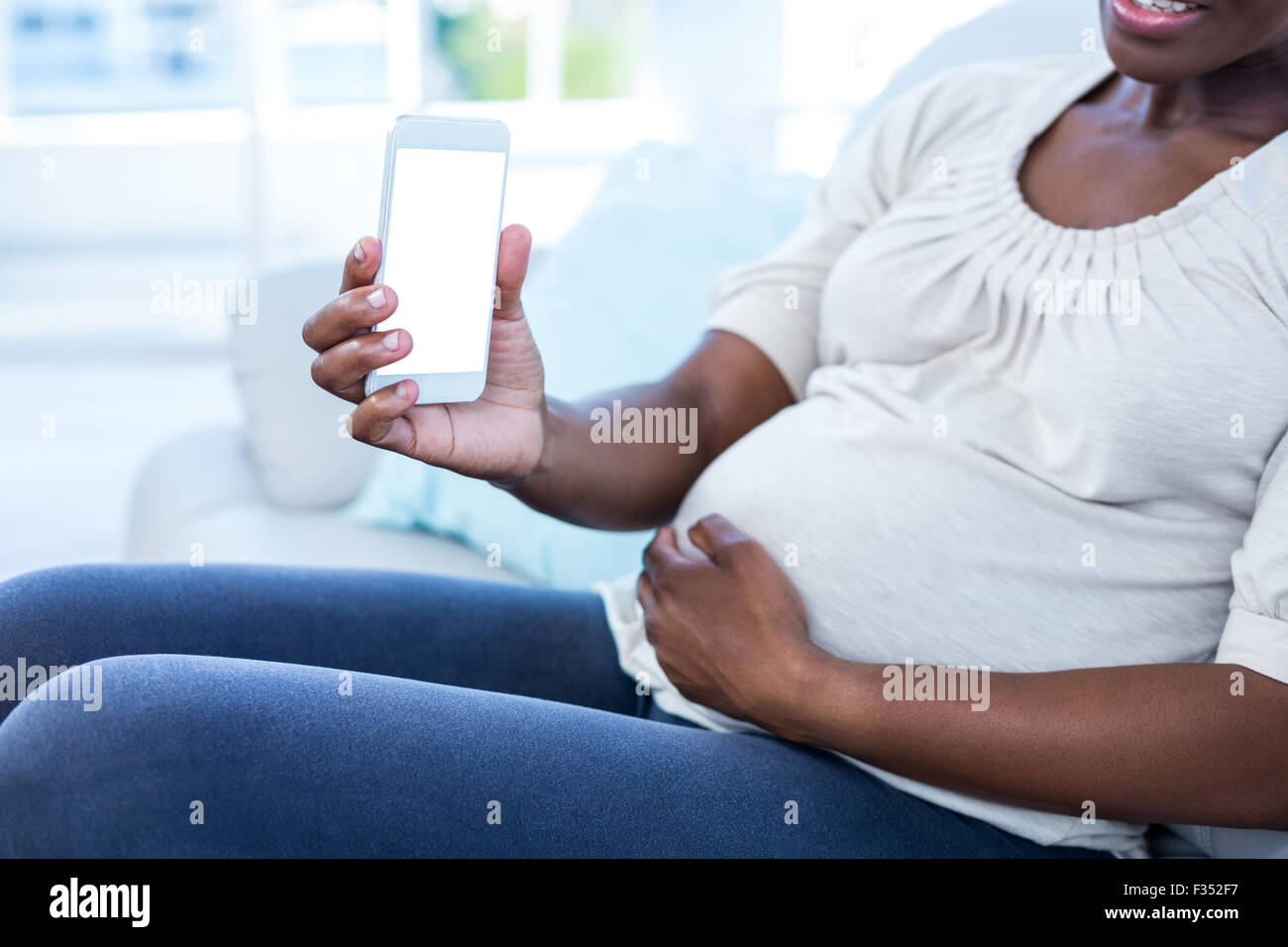 Mid section of pregnant woman showing mobile phone Stock Photo - Alamy