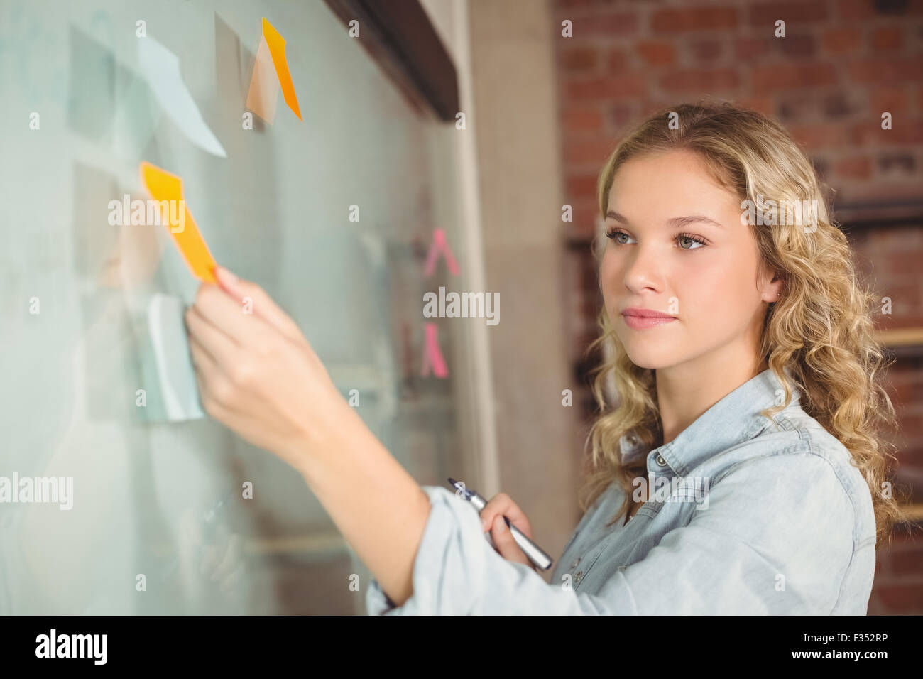 Beautiful businesswoman sticking notes on board in office Stock Photo ...