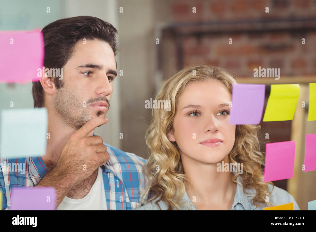Business people looking at sticky notes attached on glass Stock Photo ...