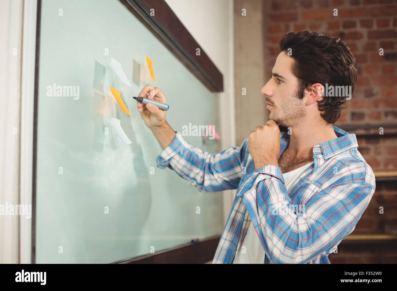Businessman holding marker while standing by glass board Stock Photo ...