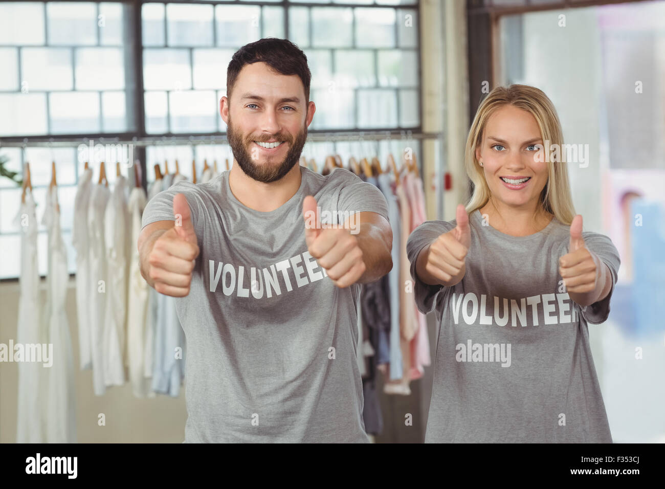 Smiling volunteers giving thumbs up Stock Photo - Alamy