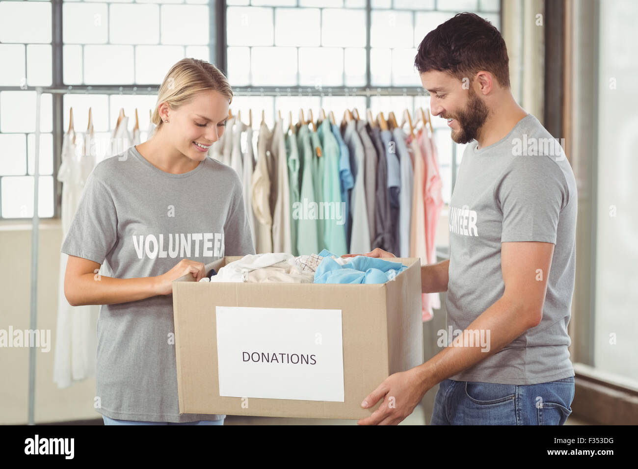 Happy volunteer looking at donation box Stock Photo - Alamy