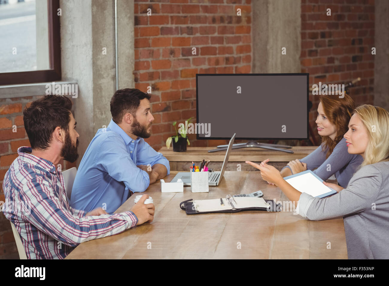 Businesswoman pointing towards male colleagues in office Stock Photo ...