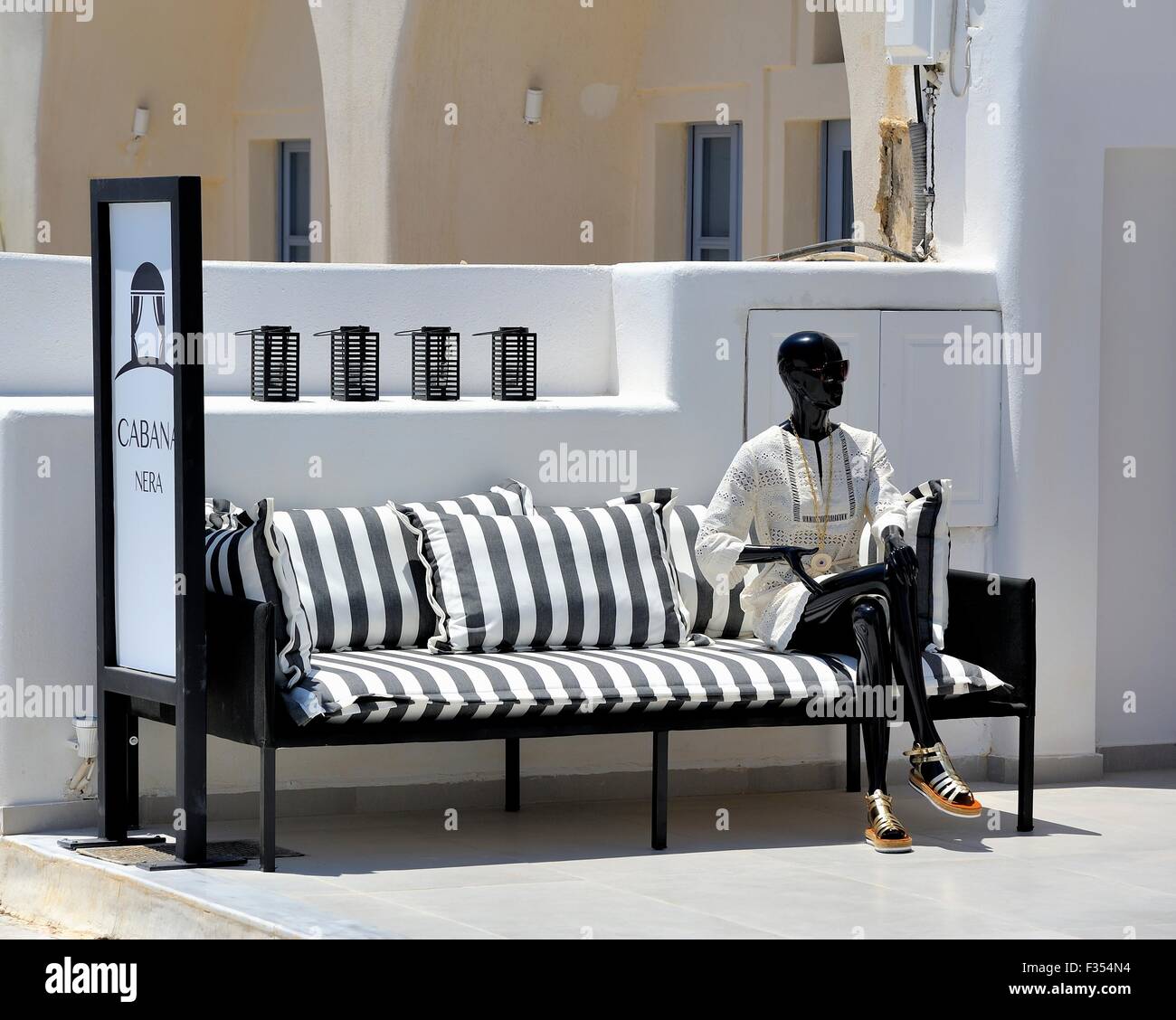 A black mannequin sitting down on a black and white bench Santorini ...