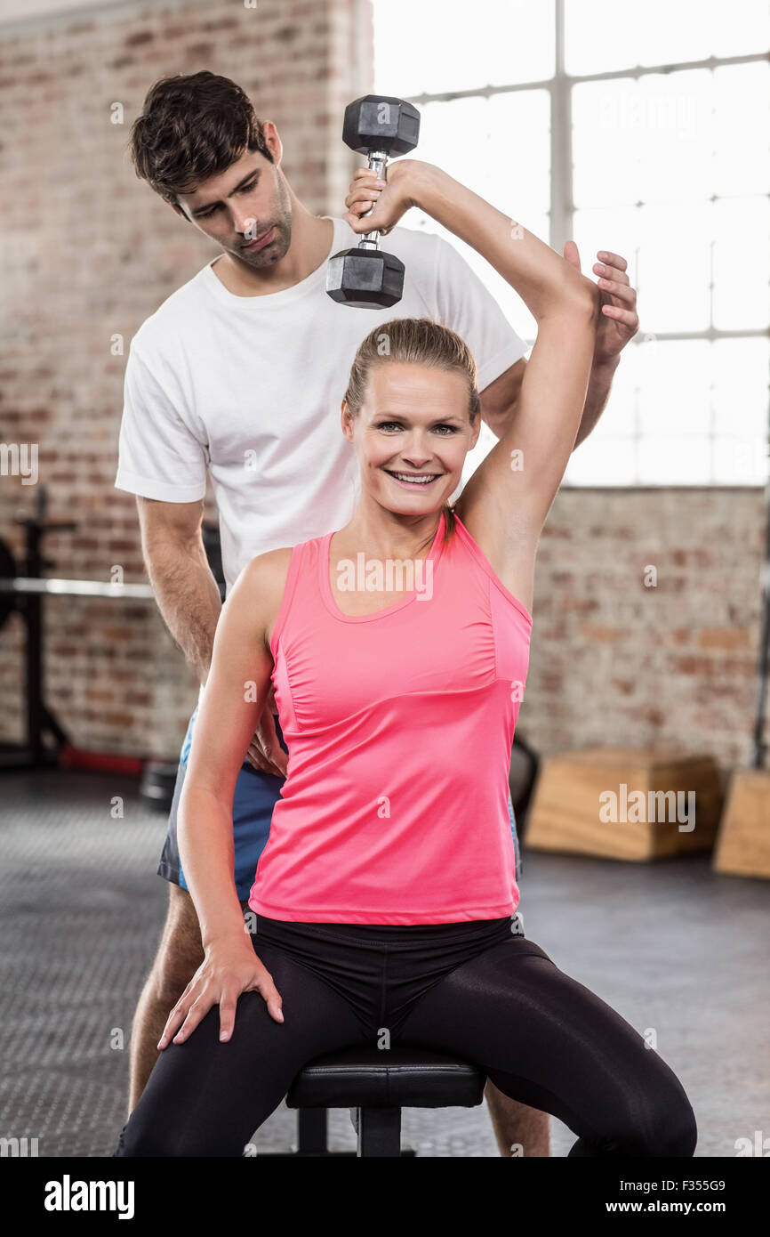 Fit woman lifting dumbbells with trainer Stock Photo - Alamy