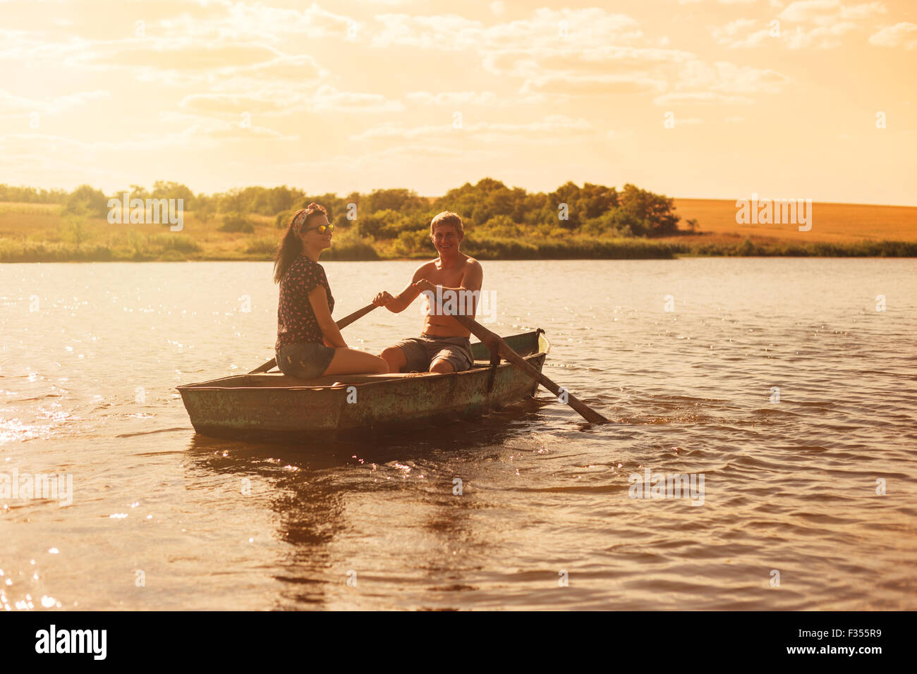 Happy romantic couple rowing a boat on lake Stock Photo - Alamy