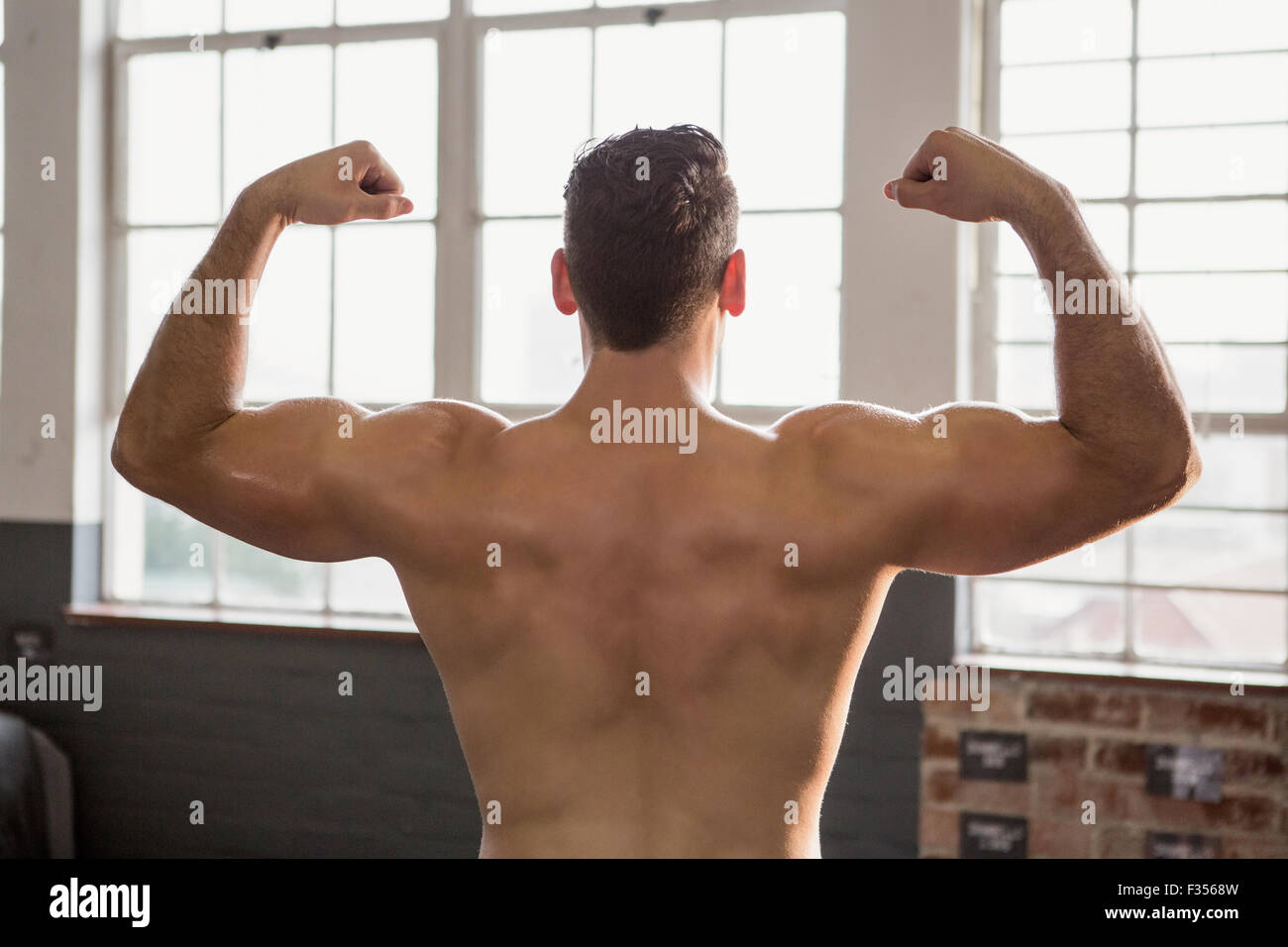 Rear view of muscular man flexing Stock Photo - Alamy