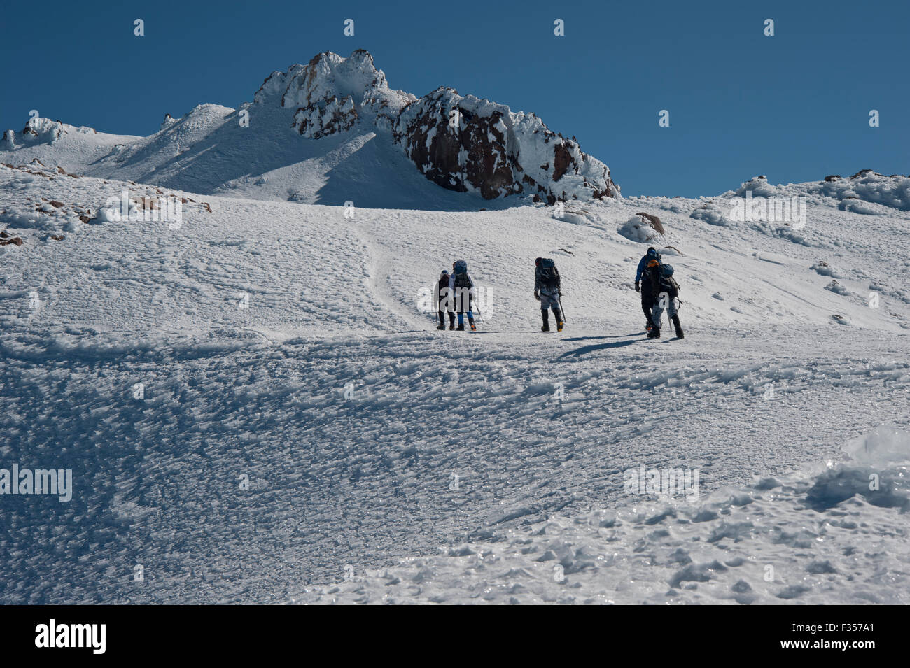 A group of people hike across a plateau as they approach their summit ...