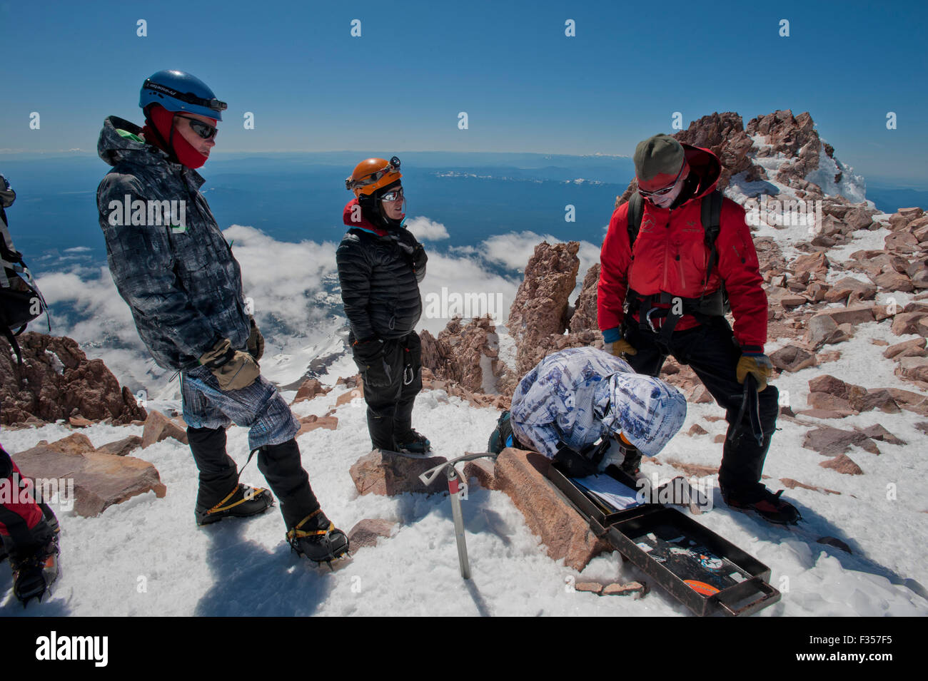 A group of people stand on the summit of Mount Shasta as a boy signs ...