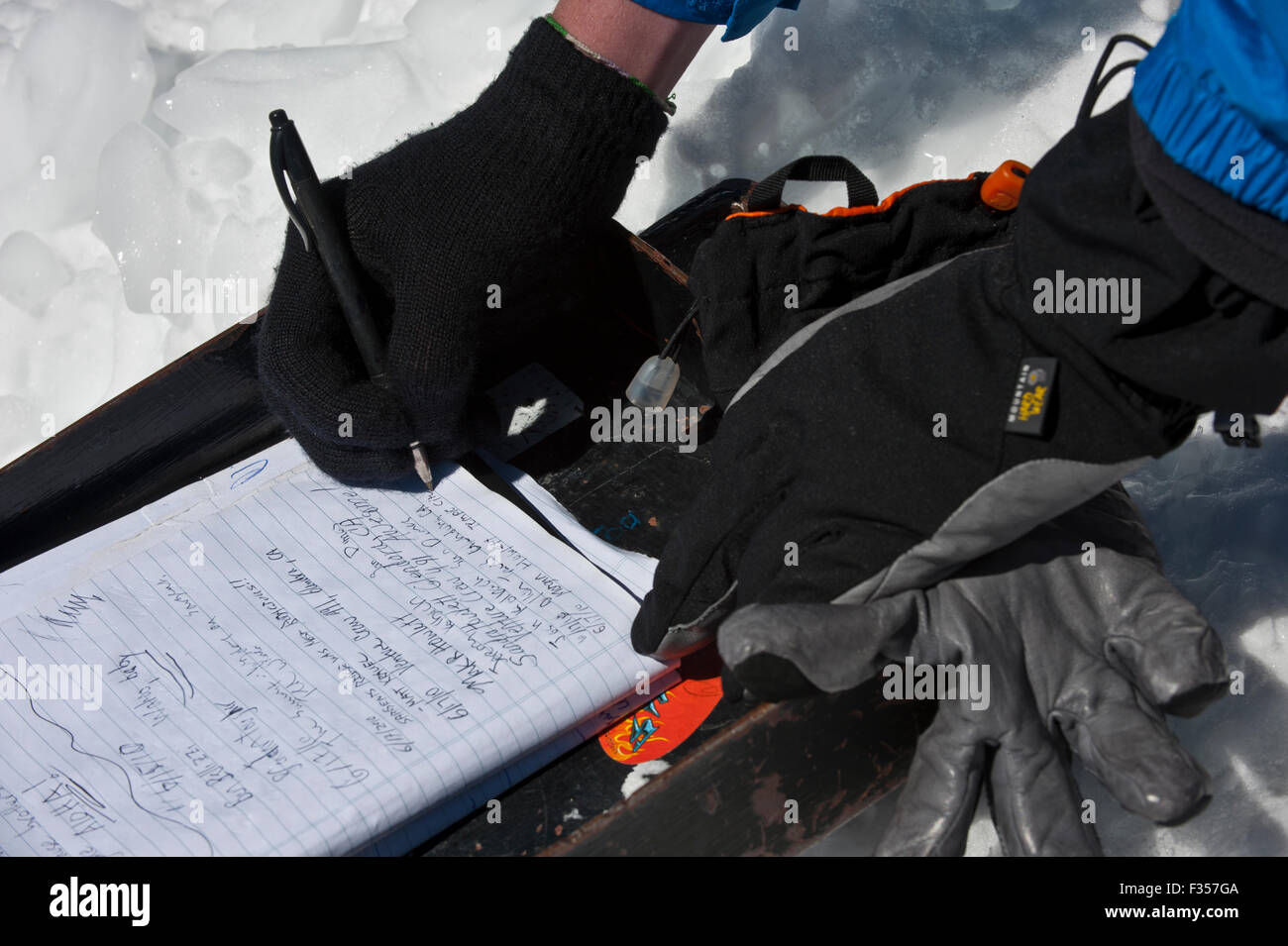 A pair of hands sign the summit register on the summit of Mount Shasta ...