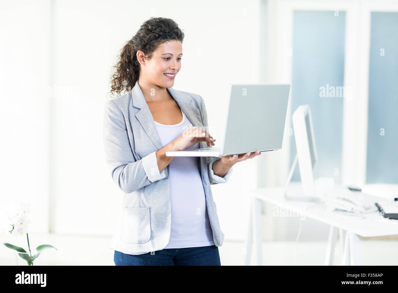 Pregnant businesswoman using laptop Stock Photo - Alamy