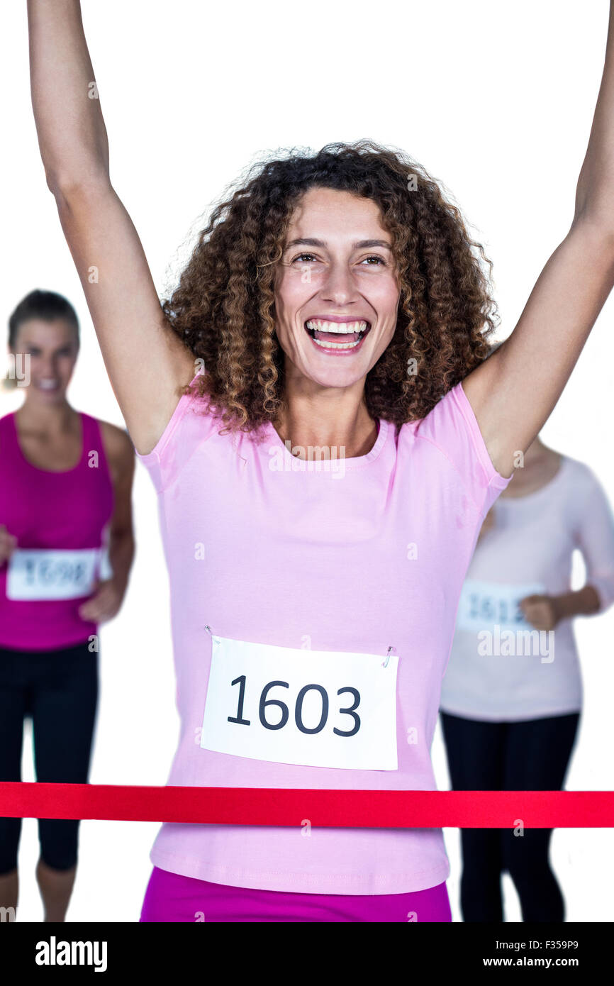 Smiling winner female athlete crossing finish line with arms raised ...