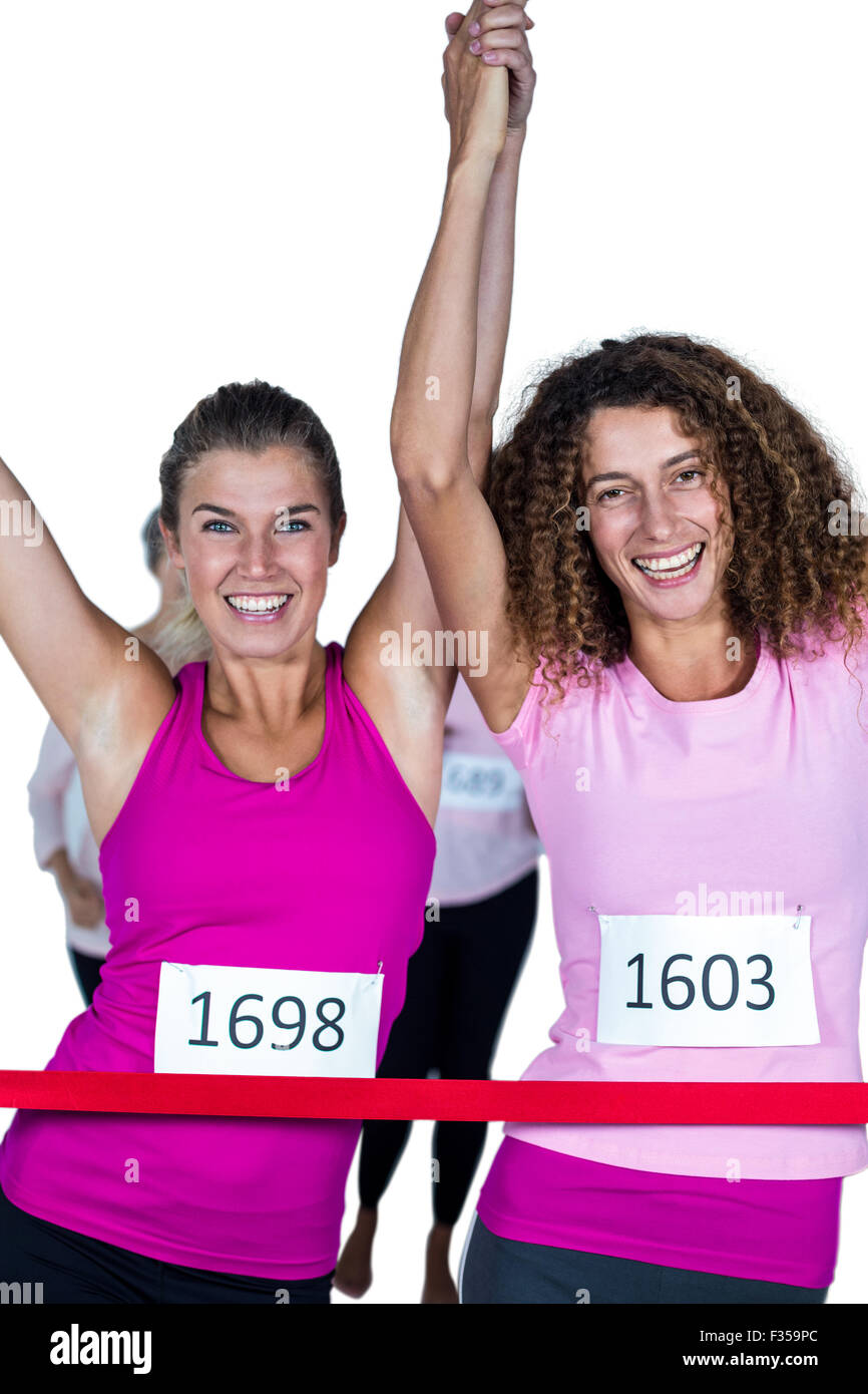 Portrait of happy winner athletes crossing finish line with arms raised ...