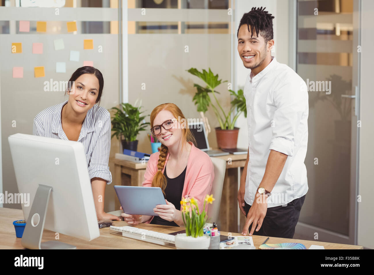Portrait of smiling business people pointing towards computer in office ...