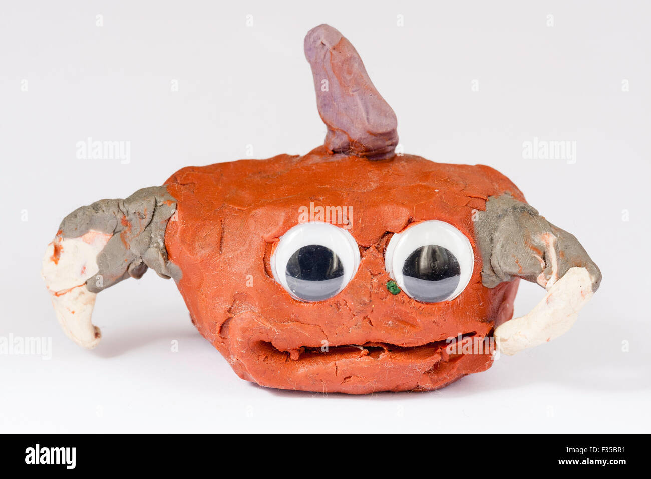 Plasticine alien model made by young child, 7-8 year old. Orange face ...