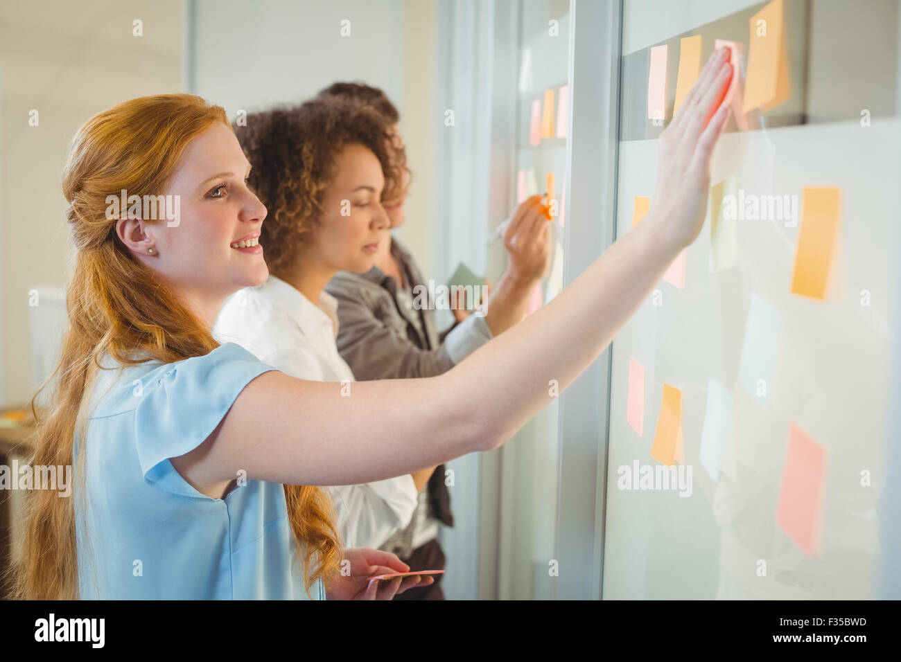 Businesswoman touching adhesive note on glass Stock Photo - Alamy
