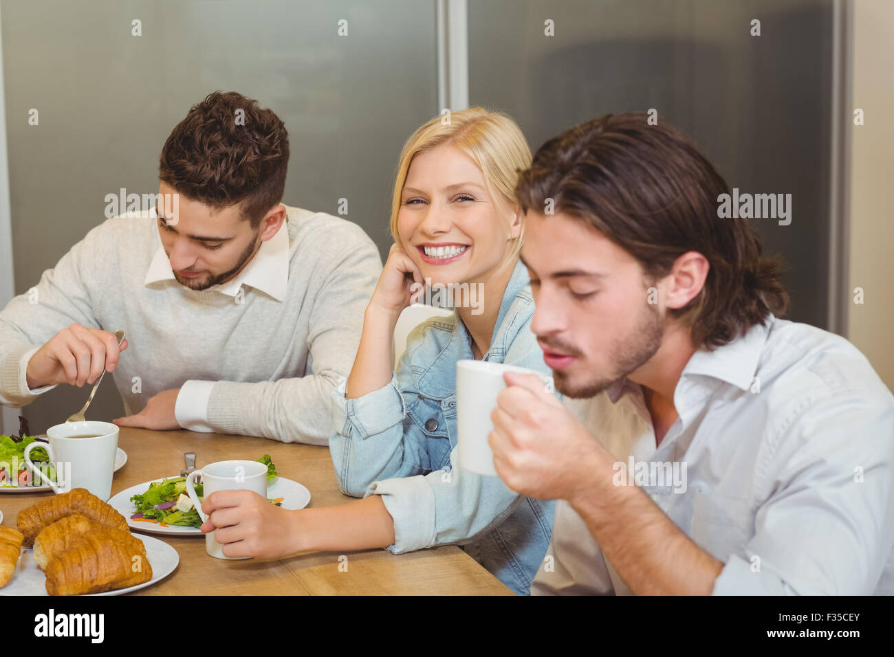 Businesswoman with male colleagues having snacks and coffee in canteen ...