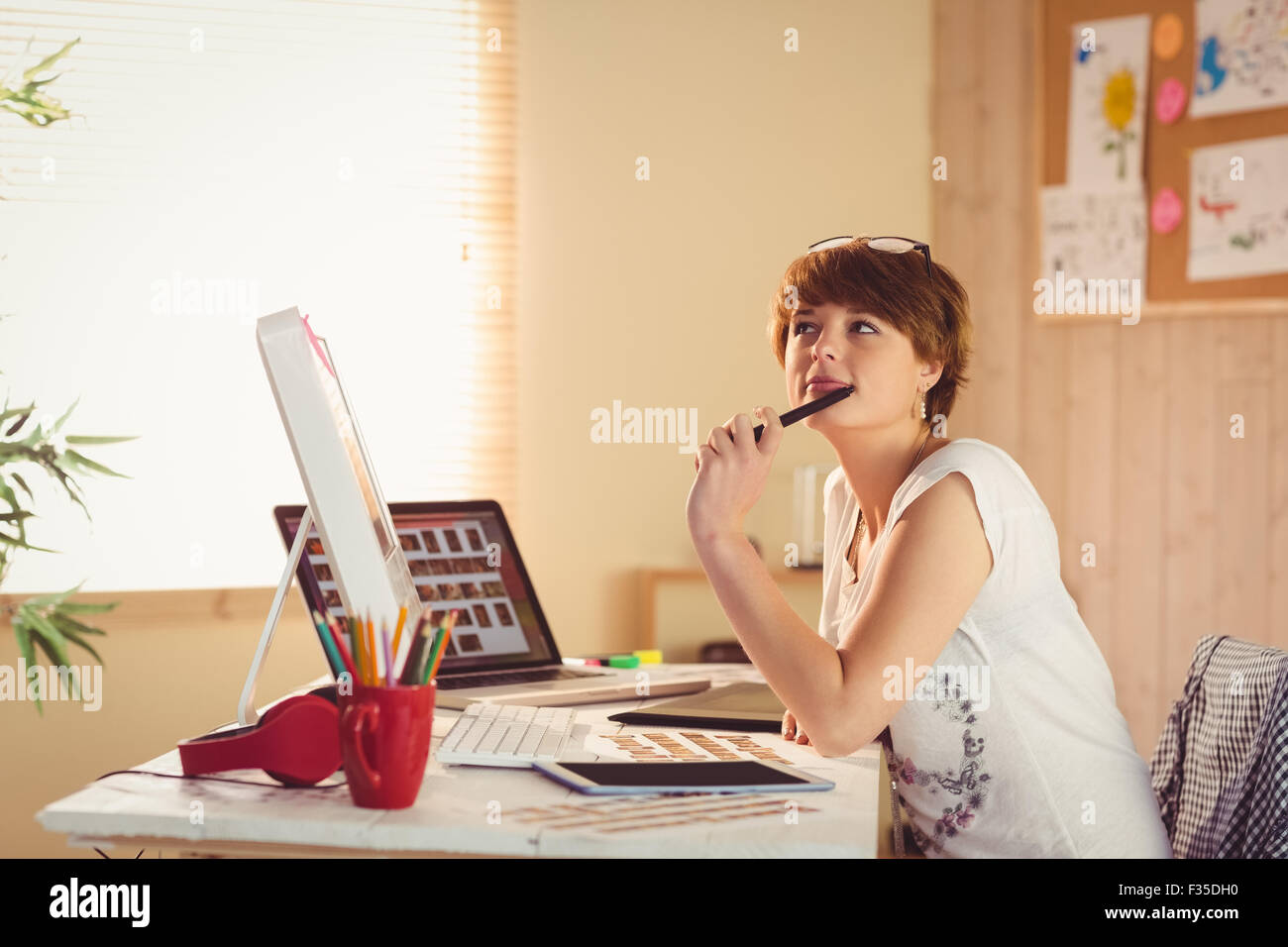 Thinking photographer looking up at her desk Stock Photo - Alamy