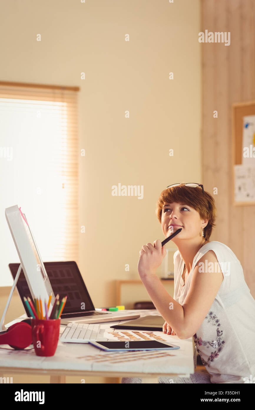 Thinking photographer looking up at her desk Stock Photo - Alamy