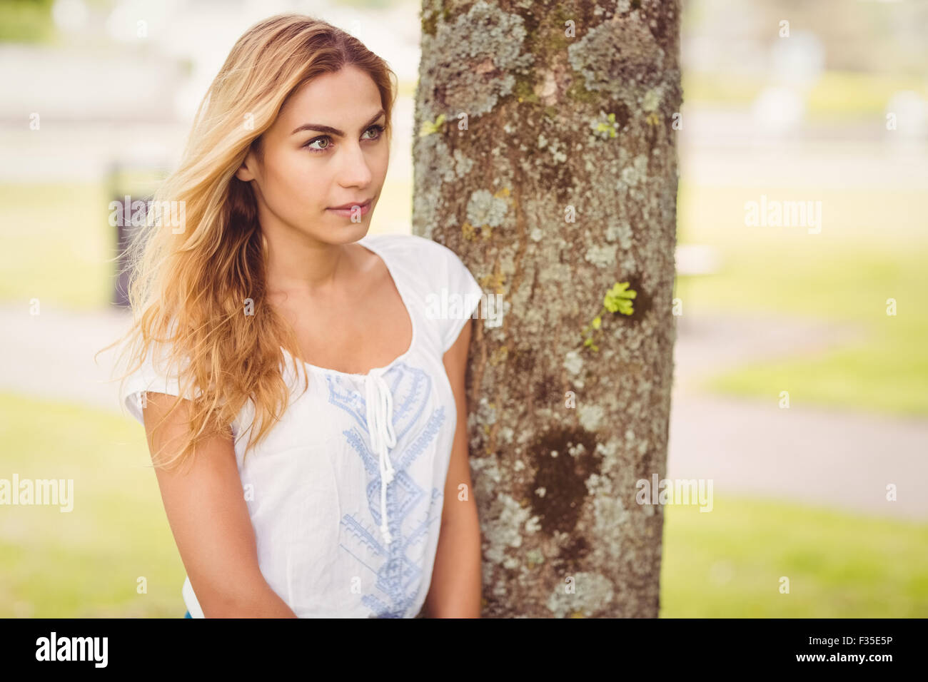 Beautiful woman standing by tree Stock Photo - Alamy