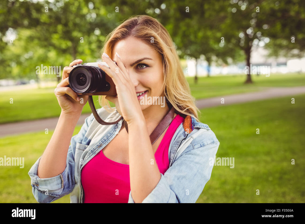 Smiling woman taking picture with camera Stock Photo - Alamy